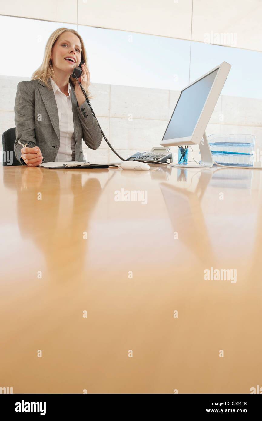 Young woman in office using phone Stock Photo - Alamy