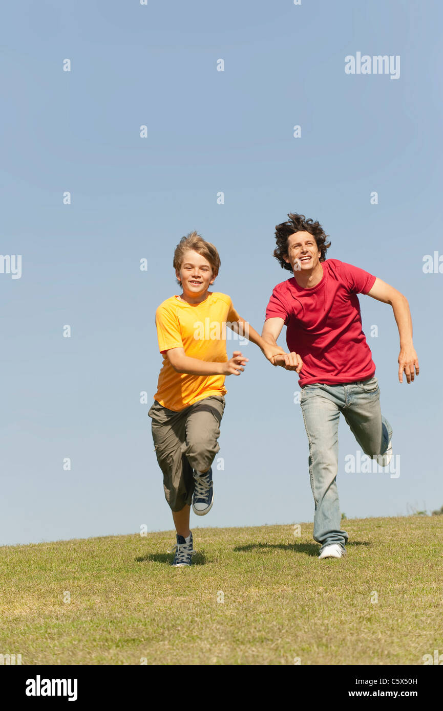Spain, Mallorca, Father and son (8-9) running hand in hand, portrait ...