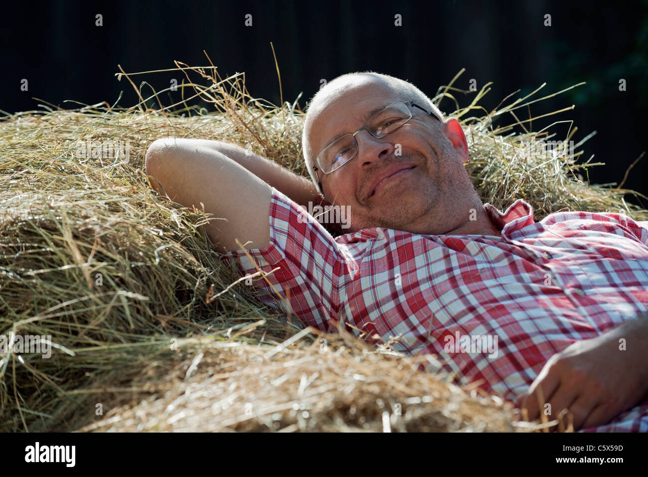 Germany, Bavaria, Senior man lying on haystack Stock Photo - Alamy