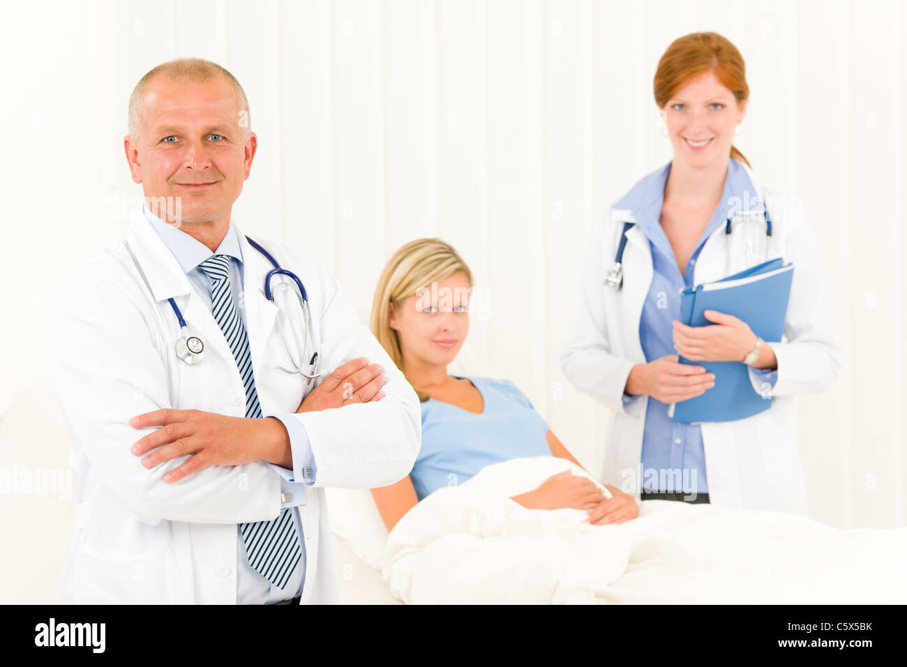 Two medical doctors professional with hospital patient lying in bed ...