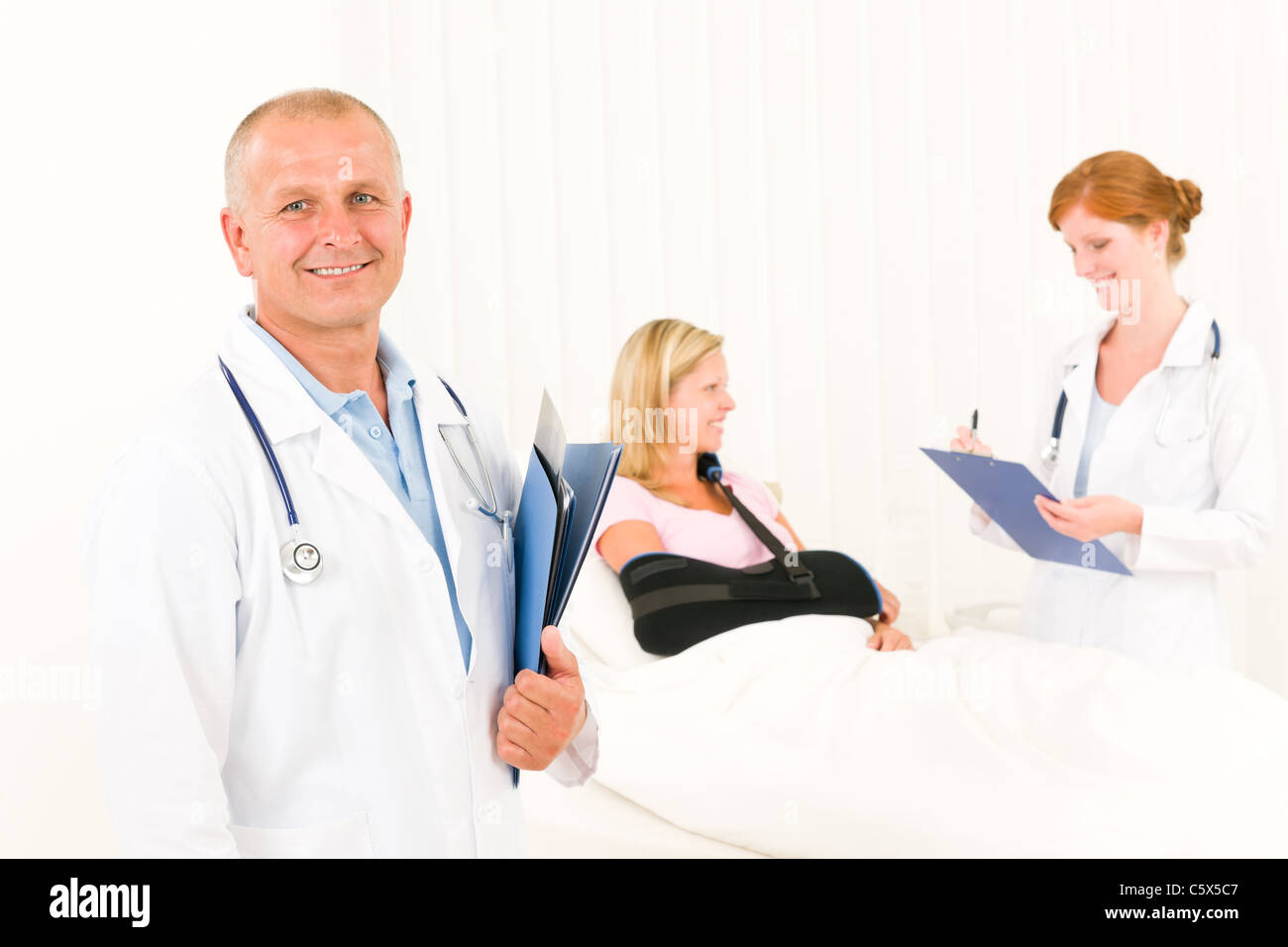 Two medical doctors professional with hospital patient lying in bed ...