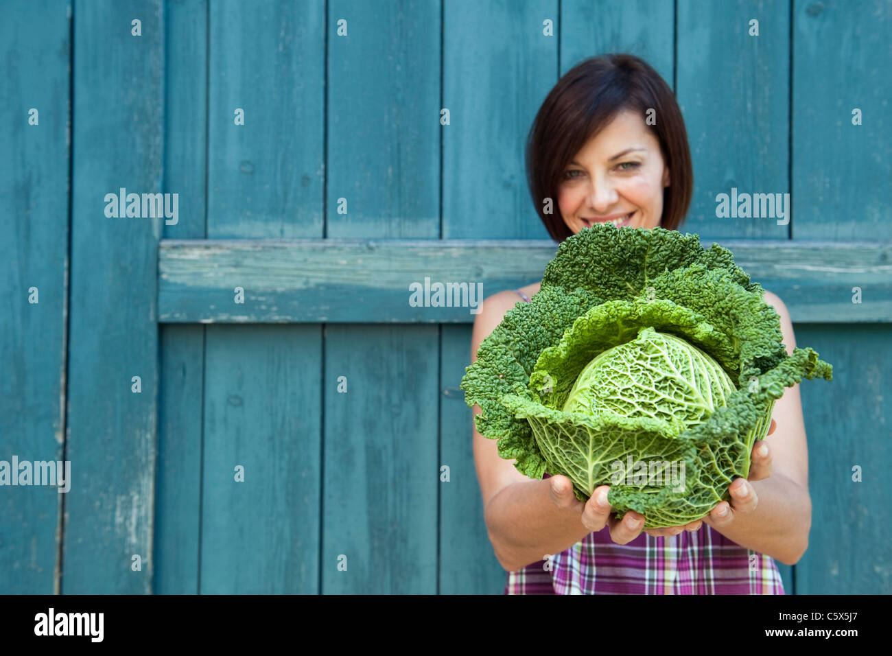 Germany, Bavaria, Woman holding savoy cabbage, smiling, portrait Stock ...