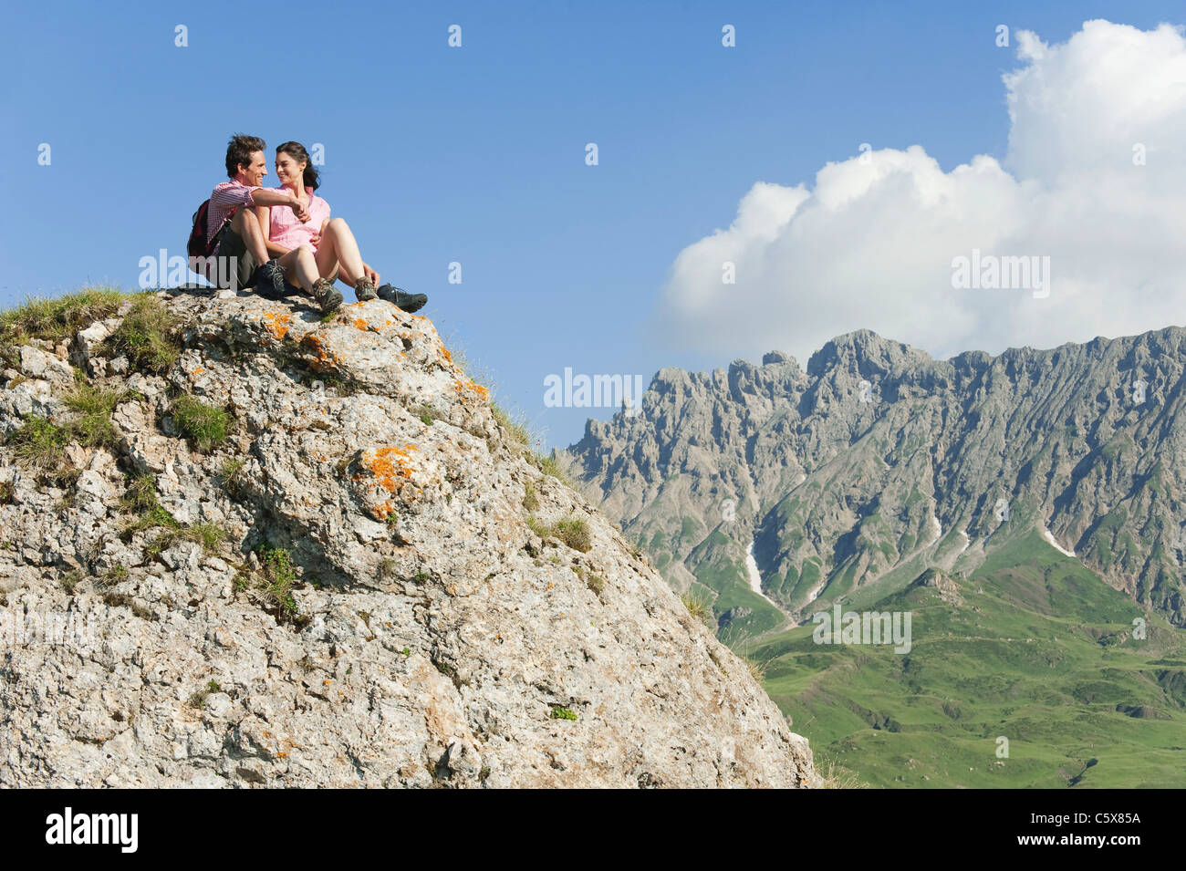 Italy, South Tyrol, Couple sitting on rock, taking a break Stock Photo ...