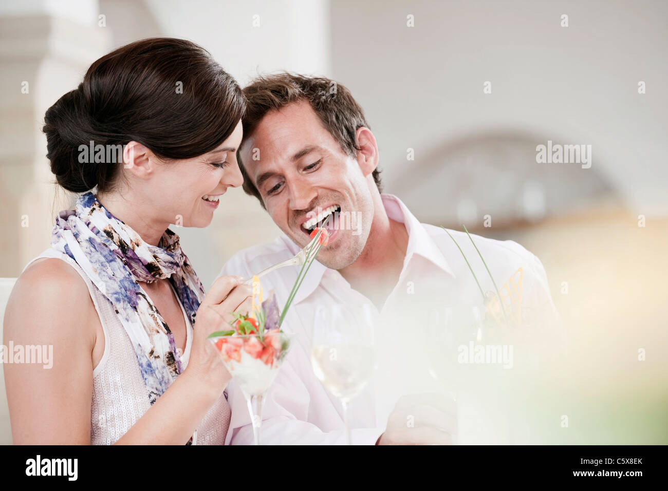 Couple sharing dessert, woman spoon feeding man Stock Photo - Alamy