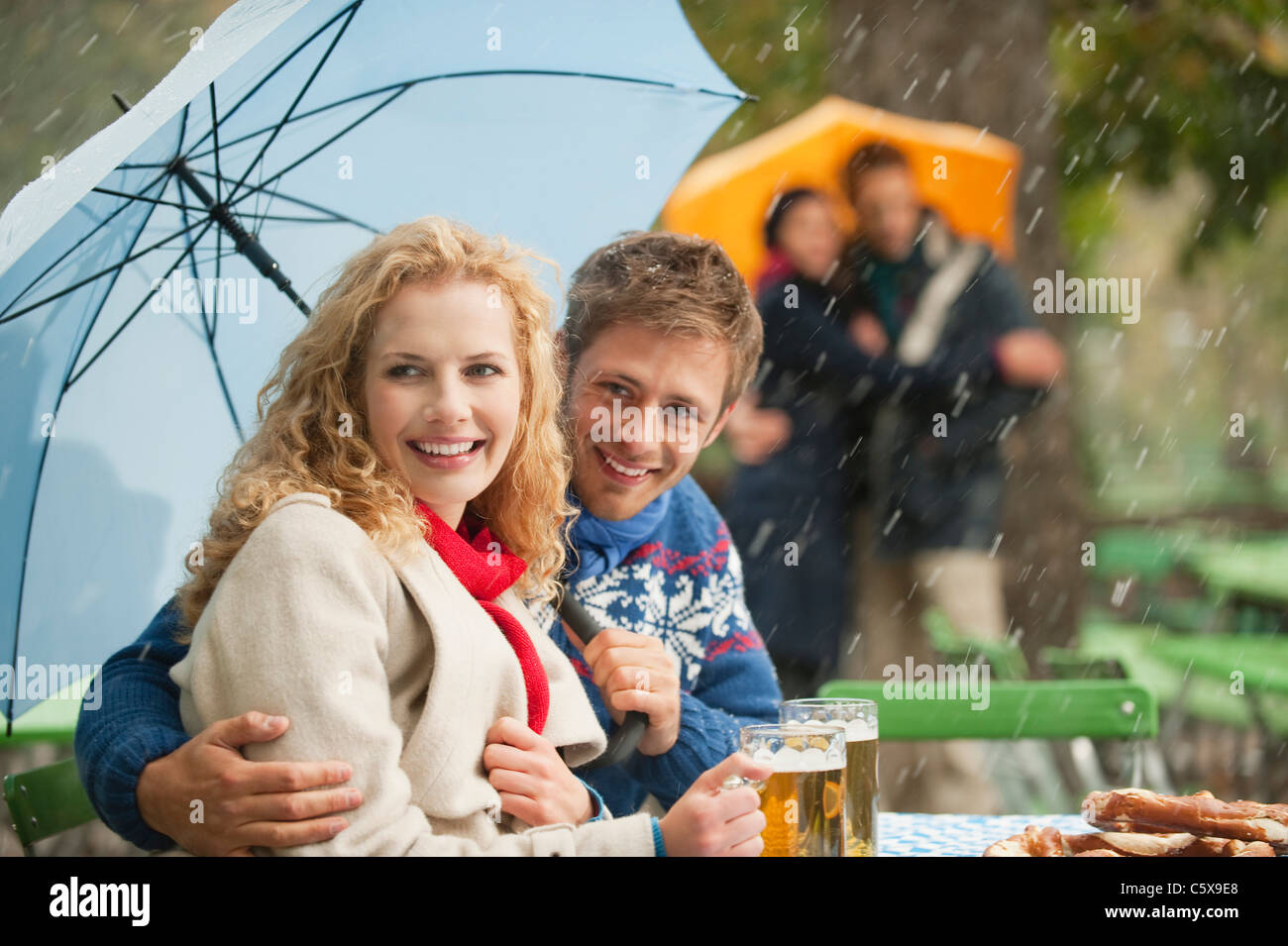 Germany, Bavaria, English Garden, Beer Garden, Four persons in rainy ...