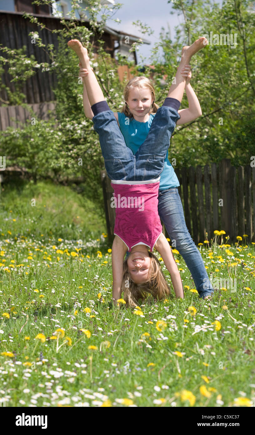 Austria, Salzkammergut, Two girls (10-11) in garden, girl helping ...