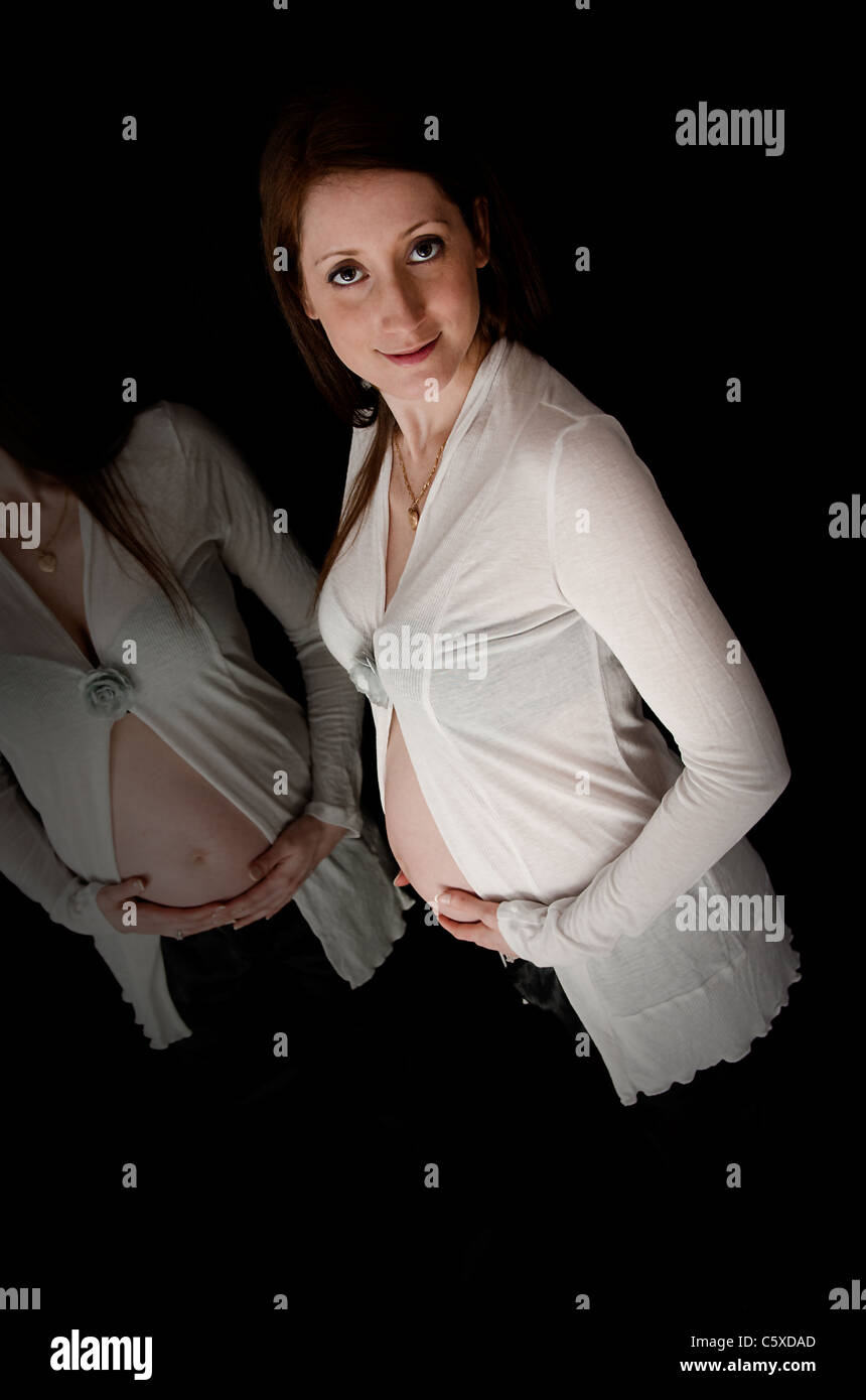 A reflection shows a to-be-mother's pregnant belly from two angles as ...