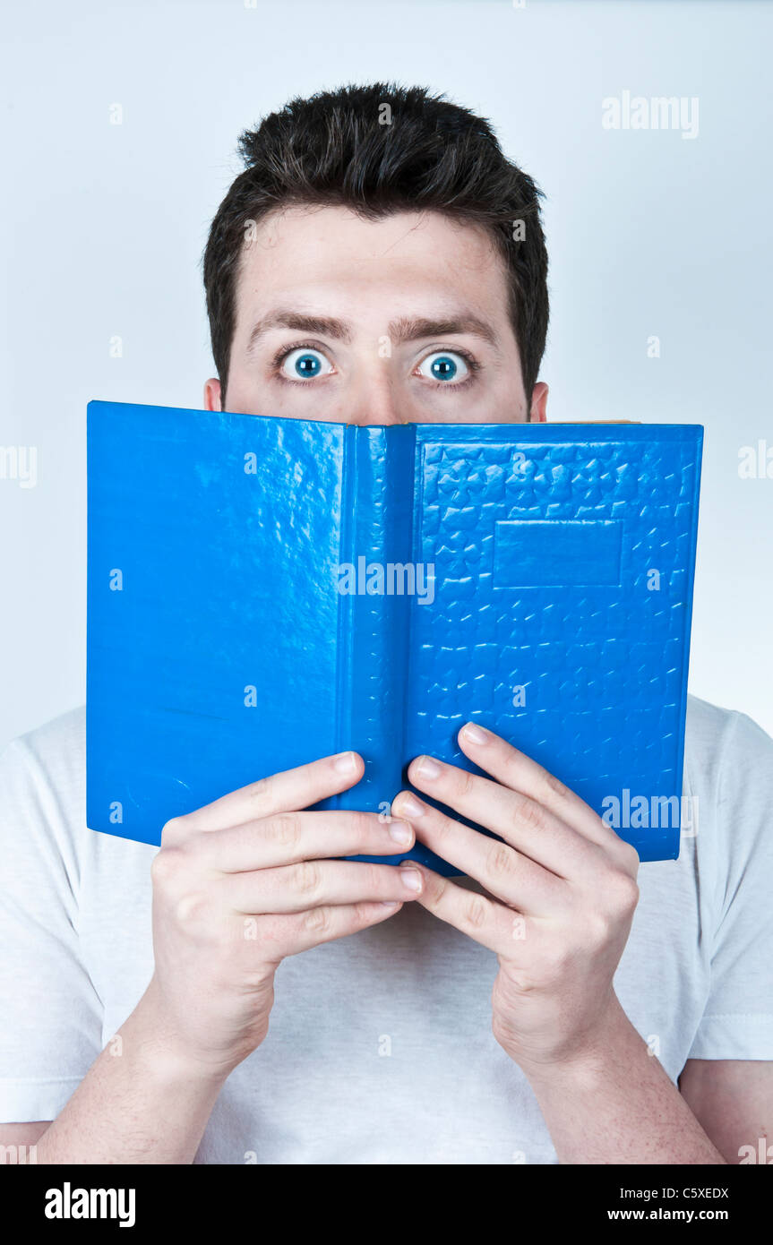 Isolated image of a young man afraid reading a book with blue hard ...