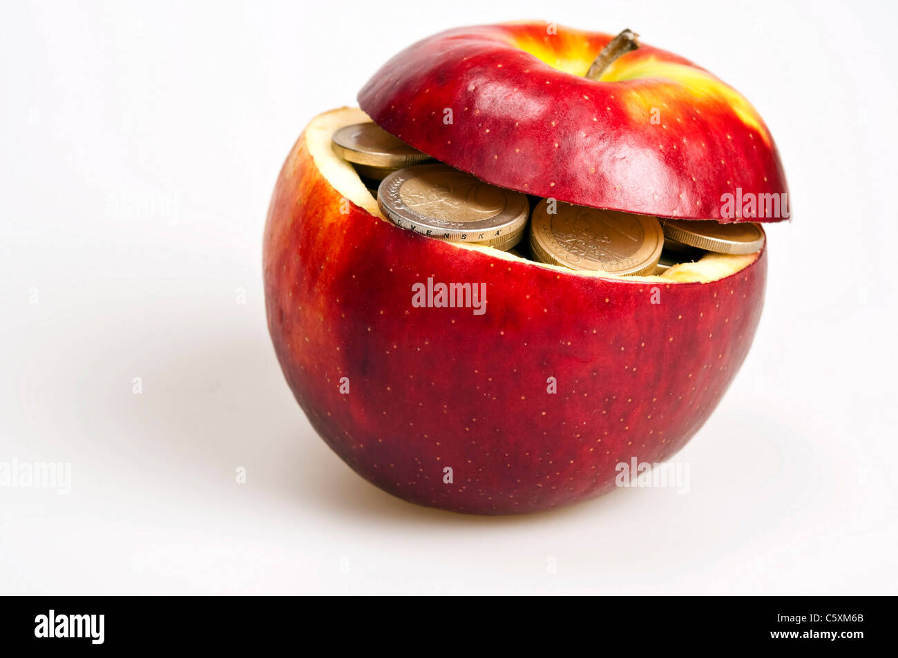 Many coins inside red apple Stock Photo - Alamy