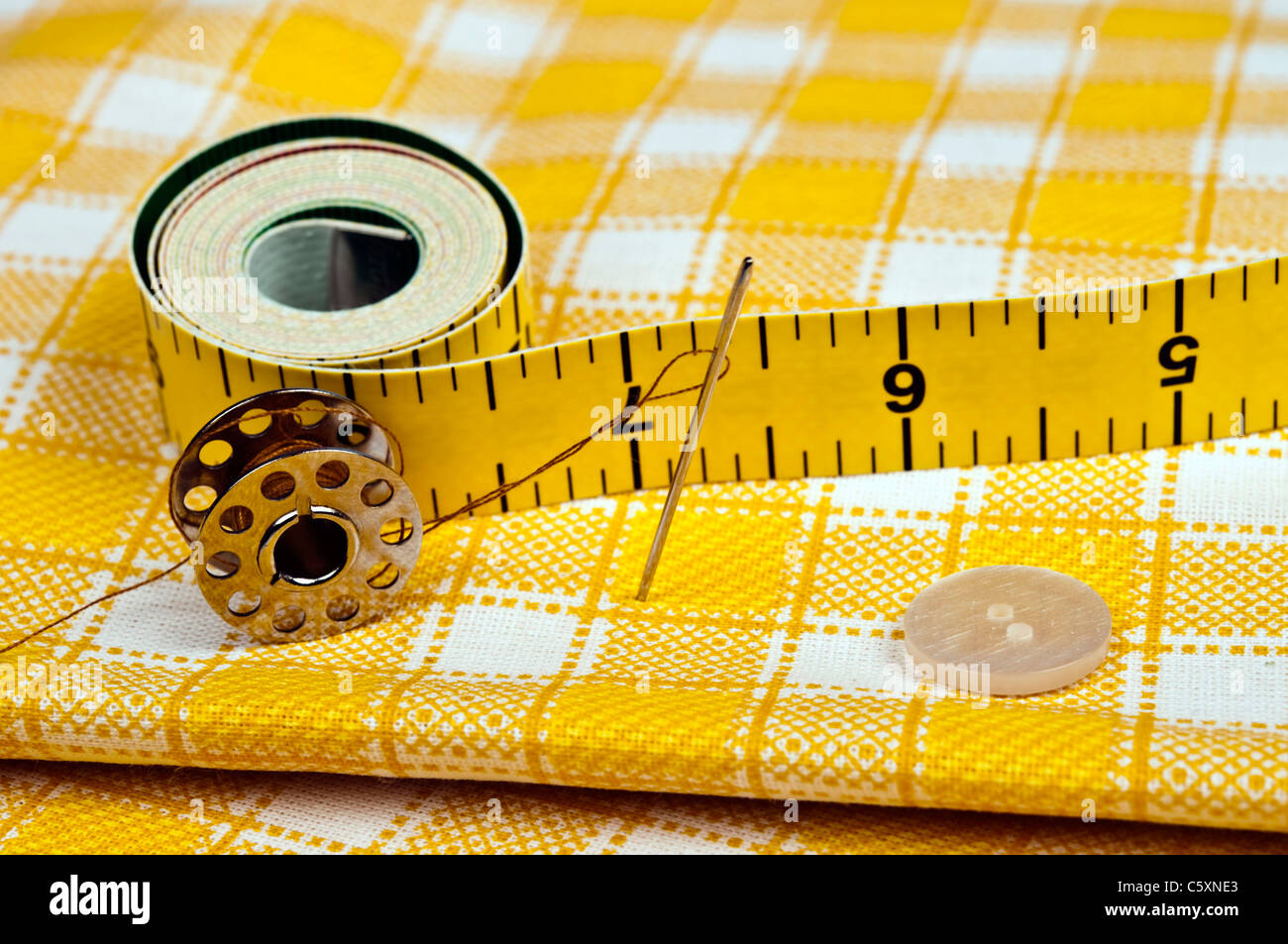 Sewing tools on yellow material Stock Photo - Alamy