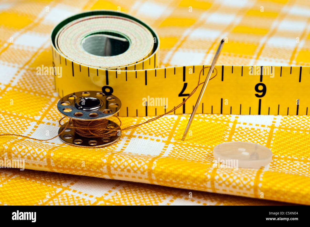 Sewing tools on yellow material Stock Photo - Alamy