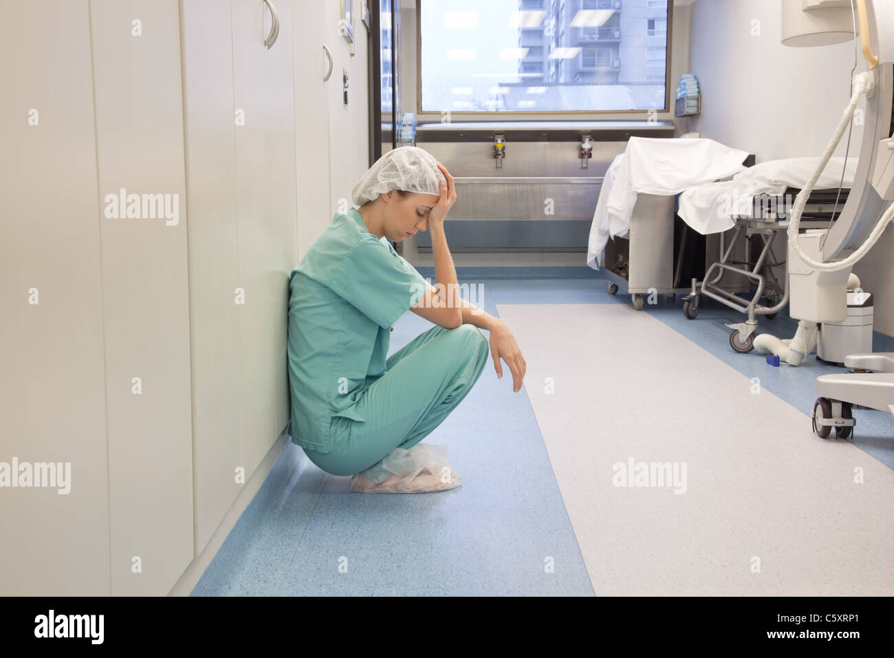 Tired doctor sitting alone in hallway Stock Photo - Alamy