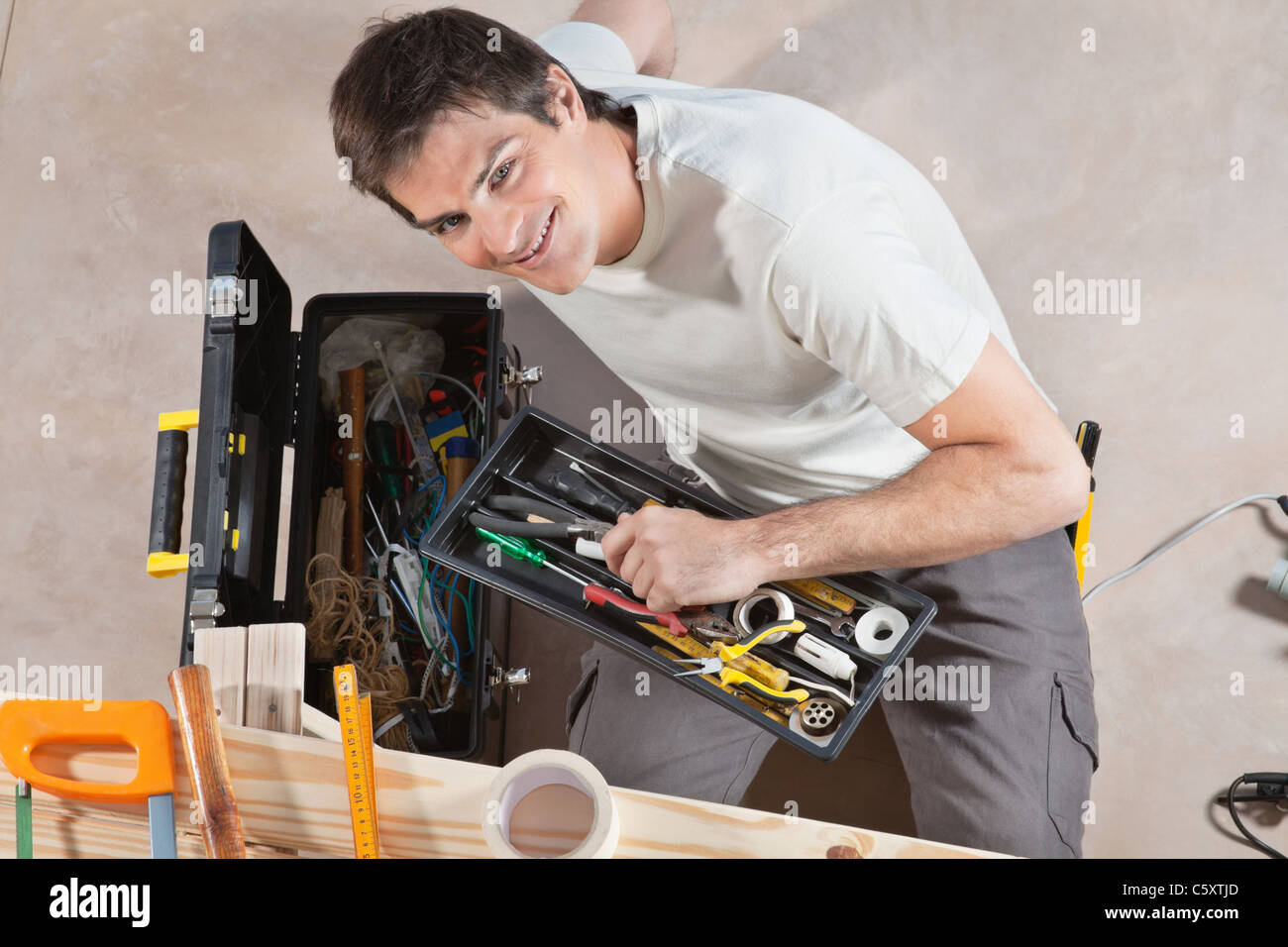 Portrait of smiling young man holding his tool box Stock Photo - Alamy