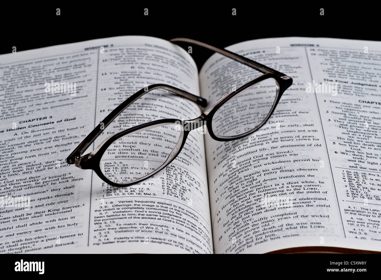 Open bible and the glasses on black background Stock Photo - Alamy