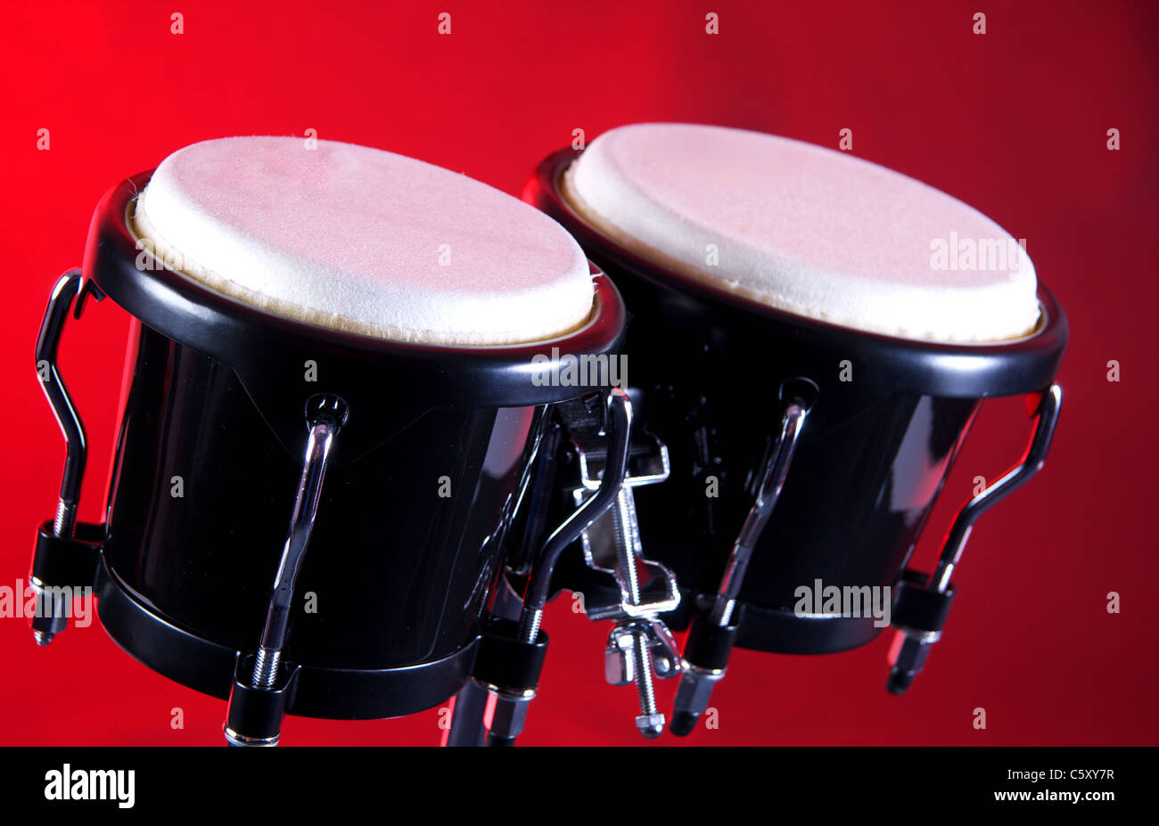 A set of black bongos isolated against a red background in the ...