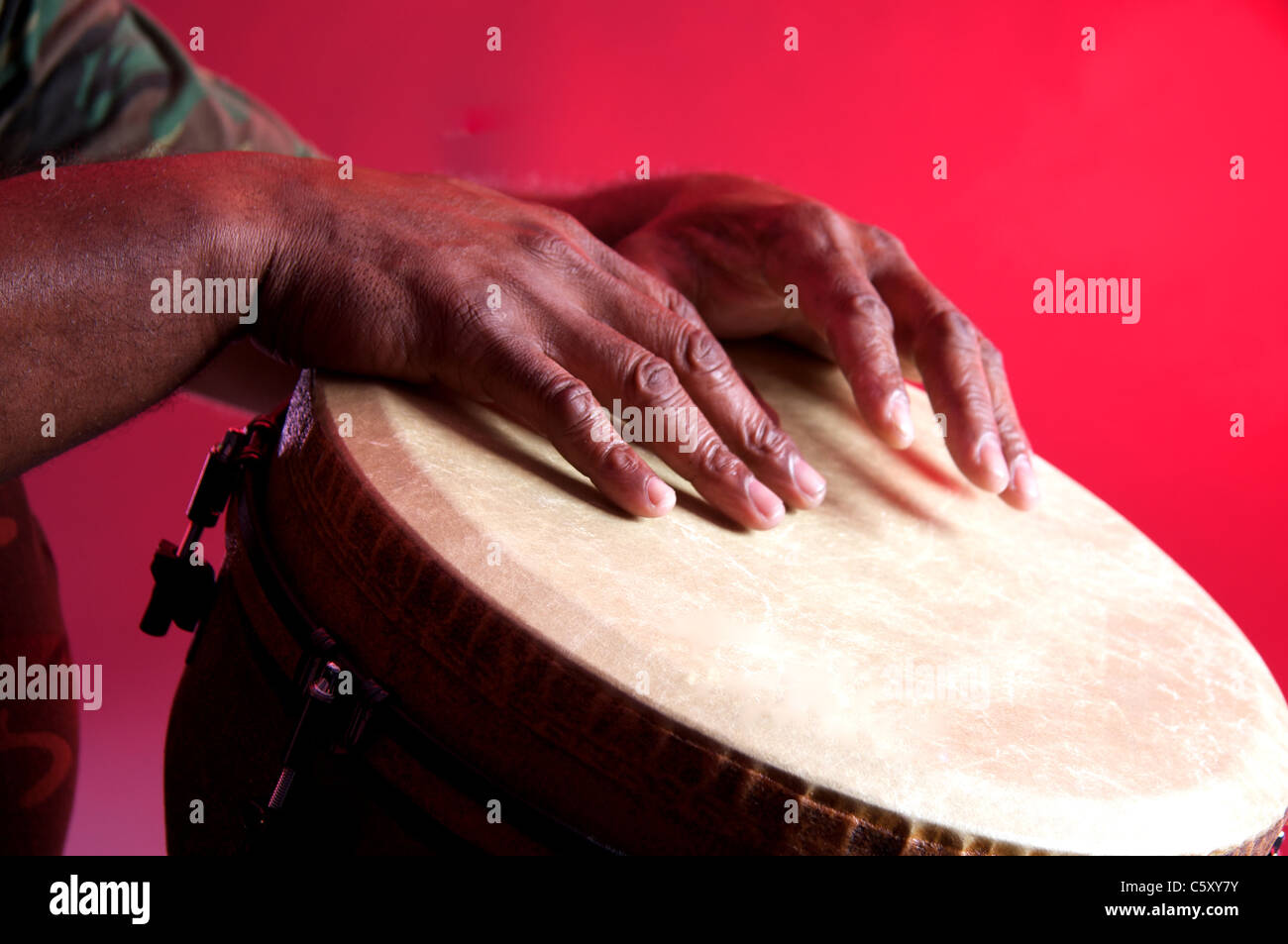 An African or Latin Djembe being played against a red background in the ...