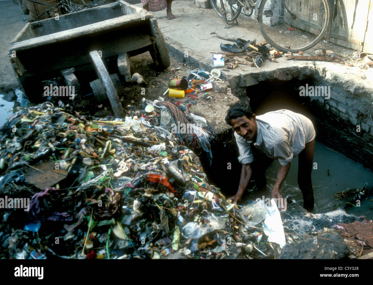 Dallit untouchable man searching for useful items to sell from a drain ...