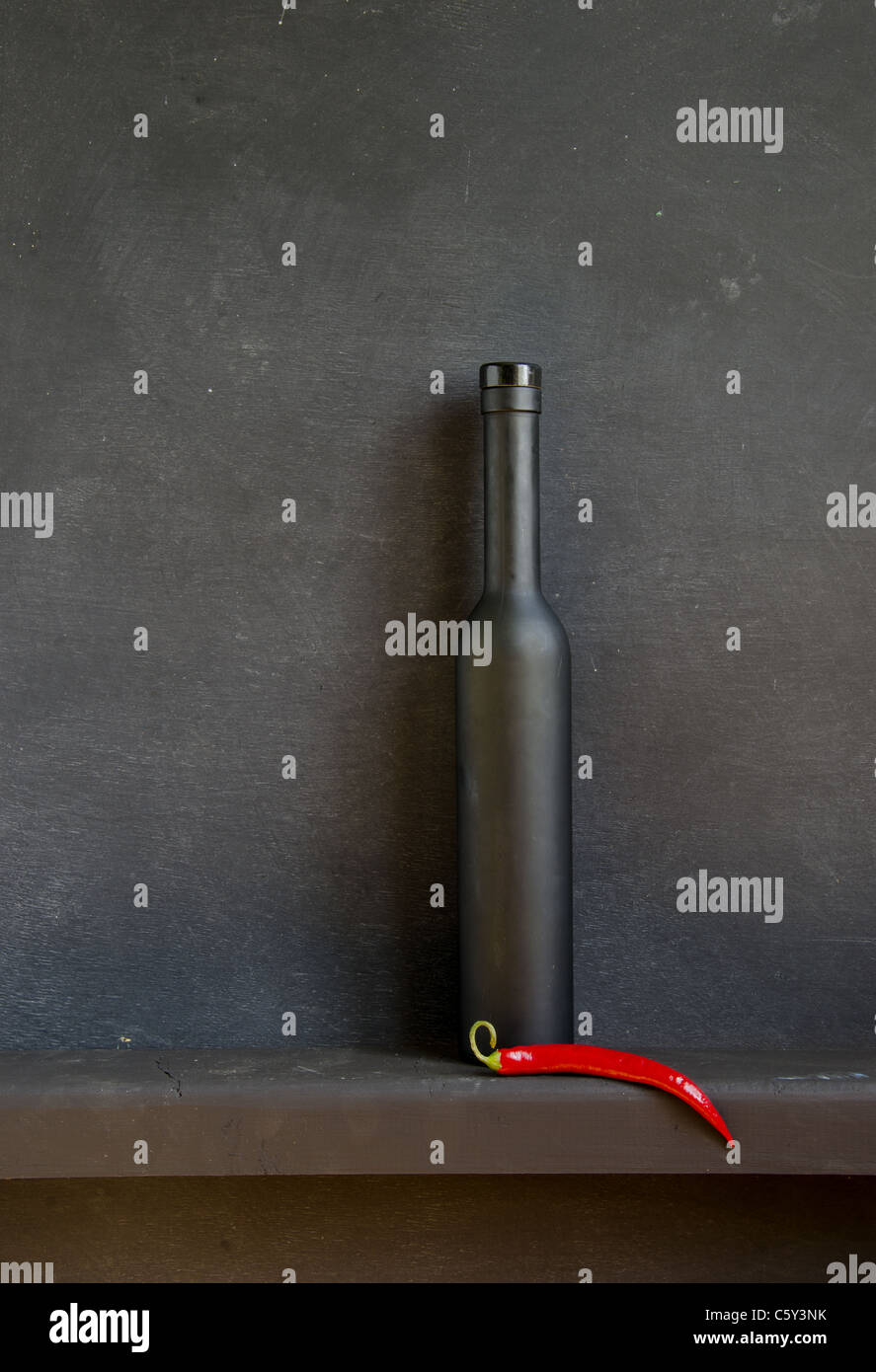 black still-life with bottle and red pepper Stock Photo - Alamy