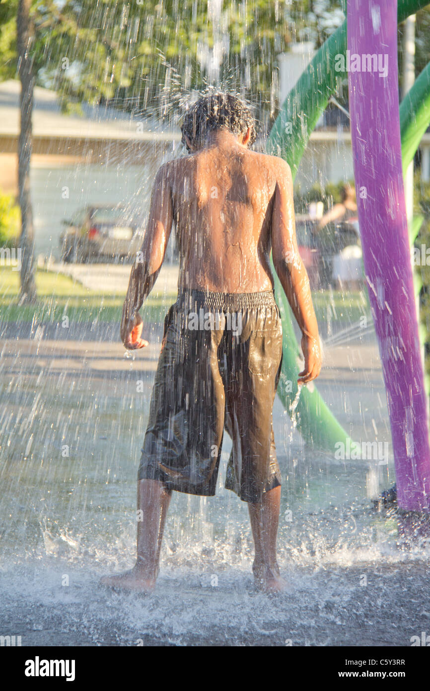A kid having fun on a hot summer day in a water splash park in Regina ...
