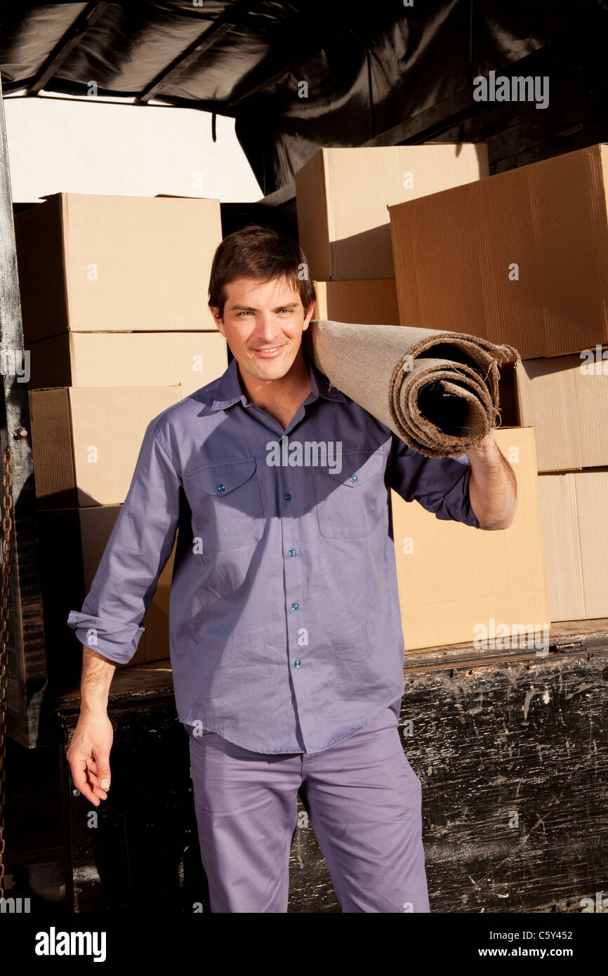 A portrait of a professional mover with a carpet and boxes in the ...