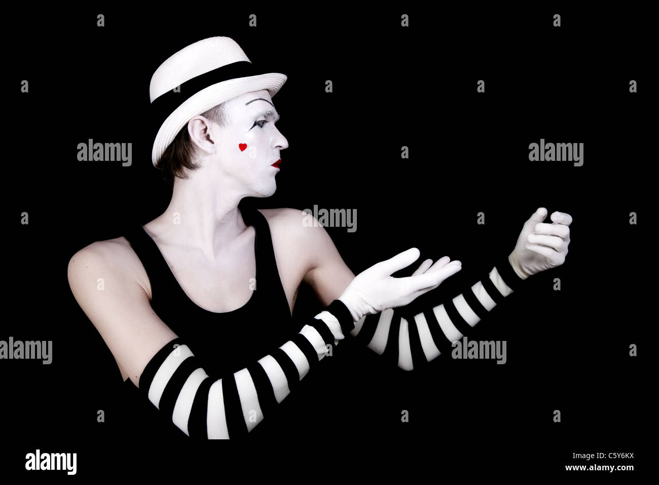 dancing mime in white hat with heart on her cheek on black background ...