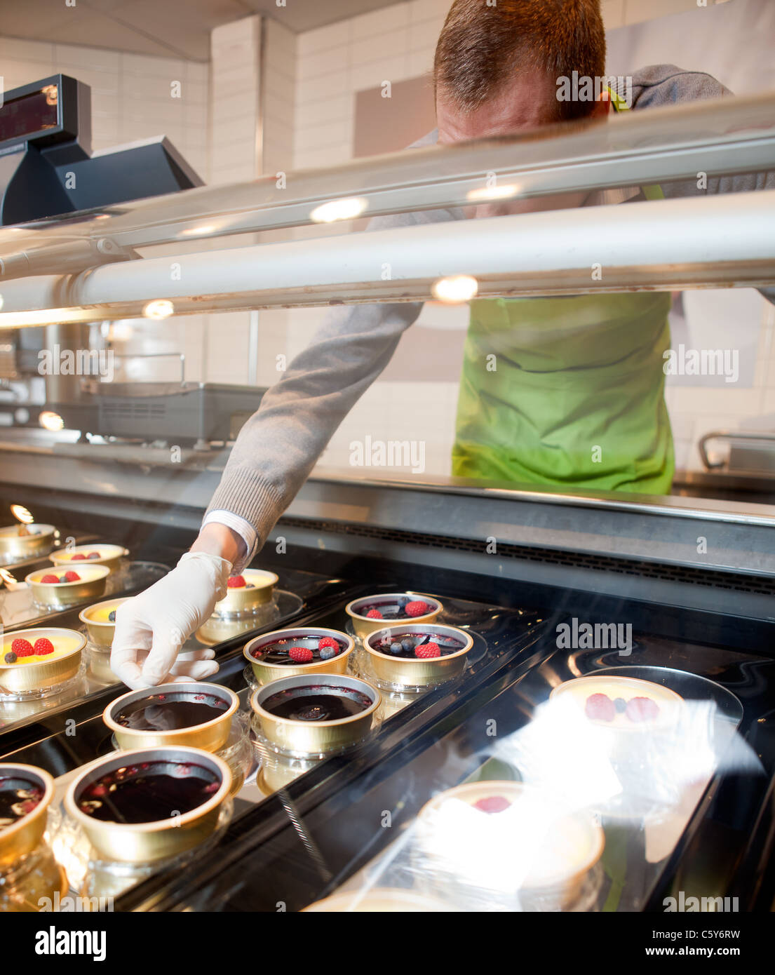 A fresh gourmet desert counter in a store with faceless chef Stock ...