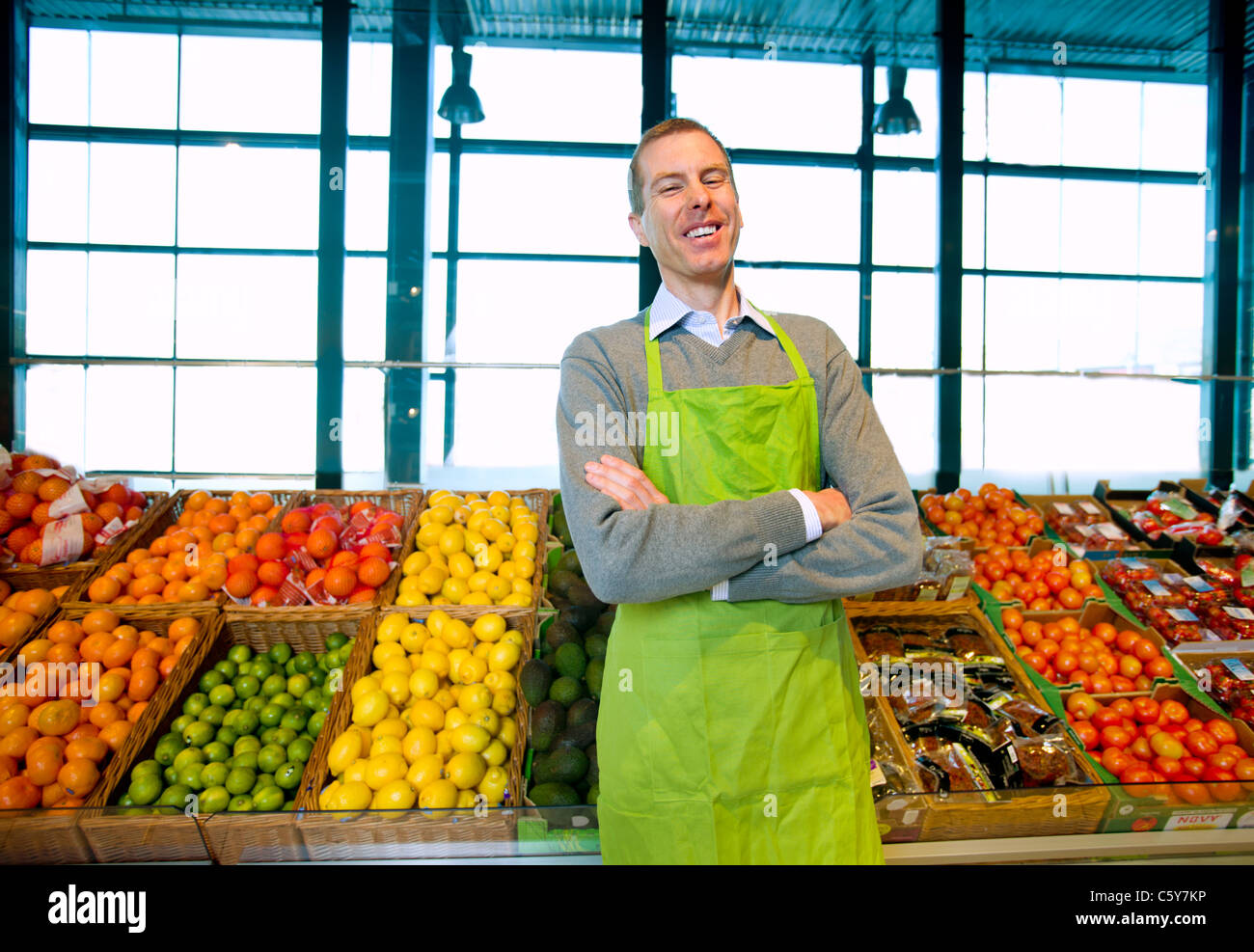A grocery store owner standing in front of vegetables and fruit Stock ...
