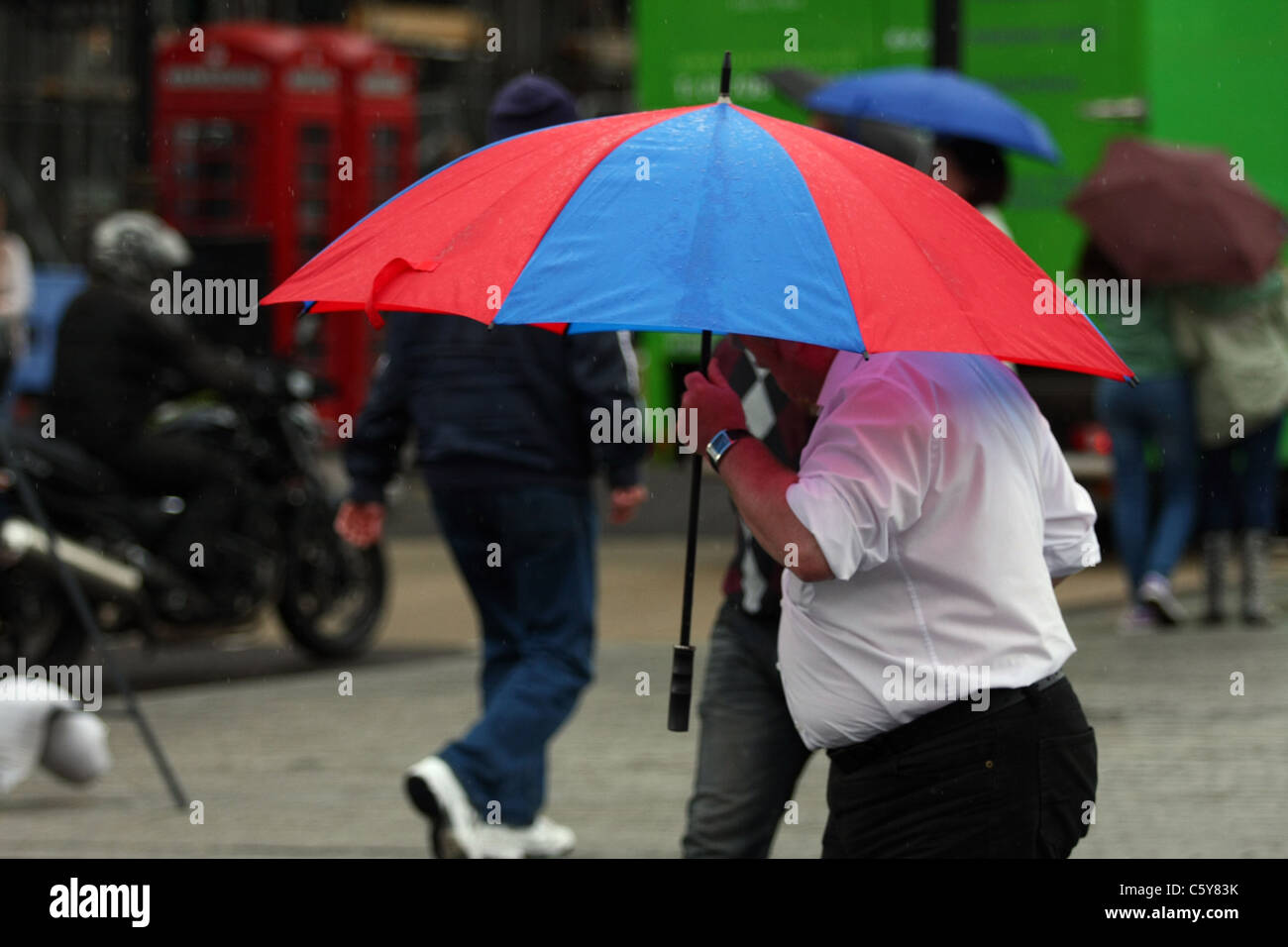 a man sheltering from the rain under his umbrella, in London Stock ...
