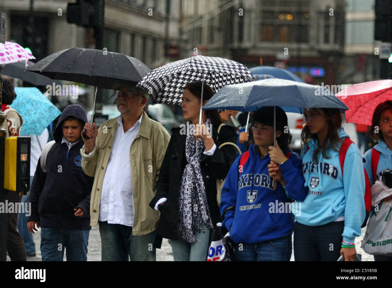 people sheltering from the rain under their umbrellas, in London Stock ...