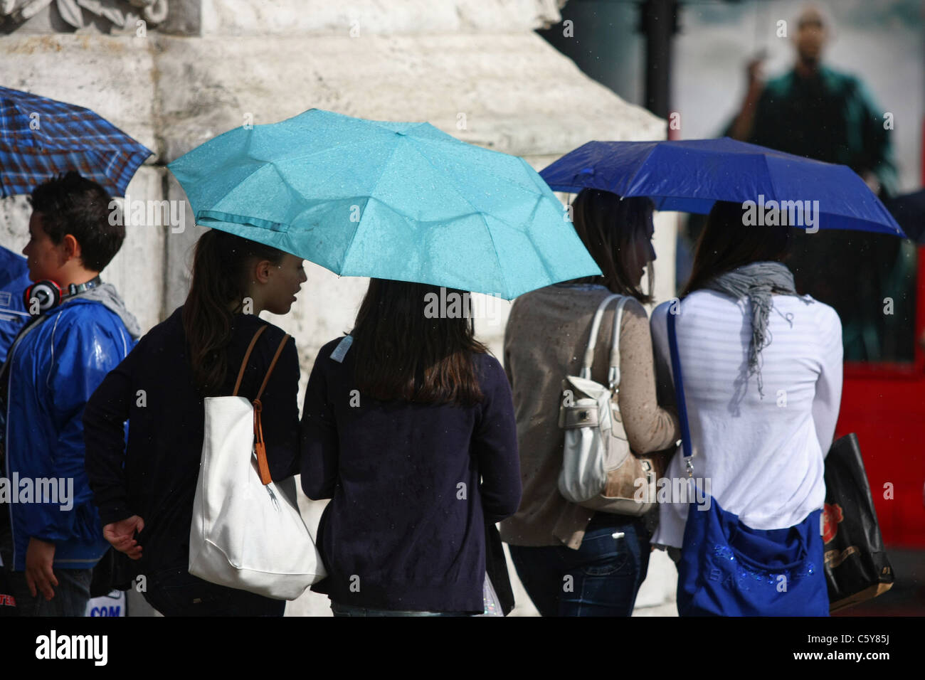 people sheltering from the rain under their umbrellas, in London Stock ...