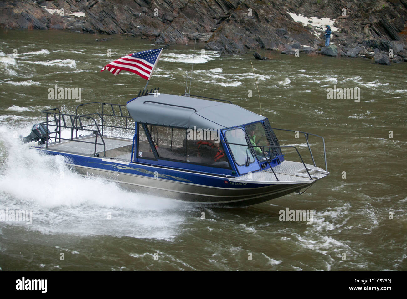 A blue and silver passenger jet boat waving an American flag travels ...