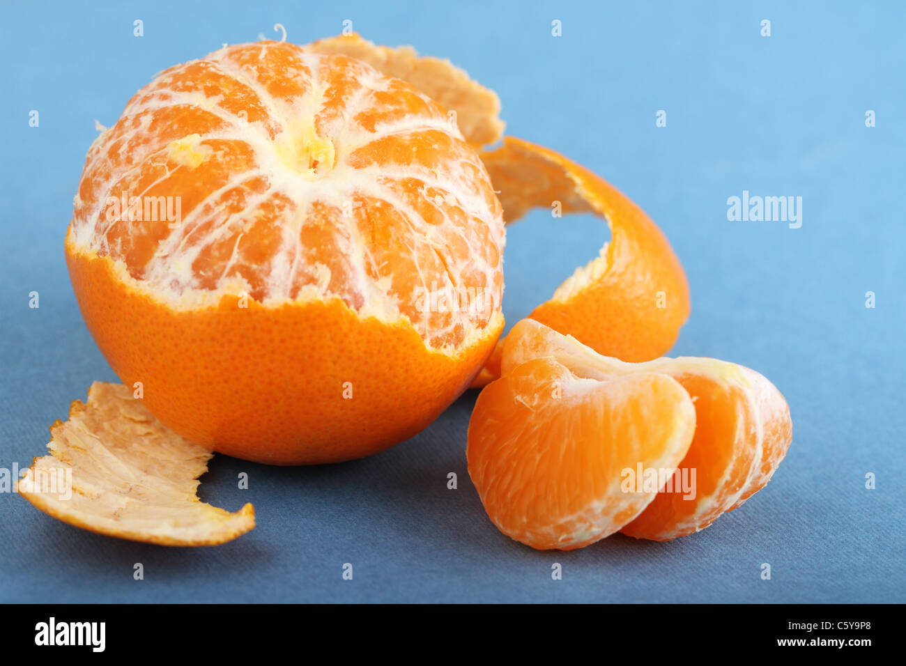 Tangerine with peeled skin on the blue background Stock Photo - Alamy