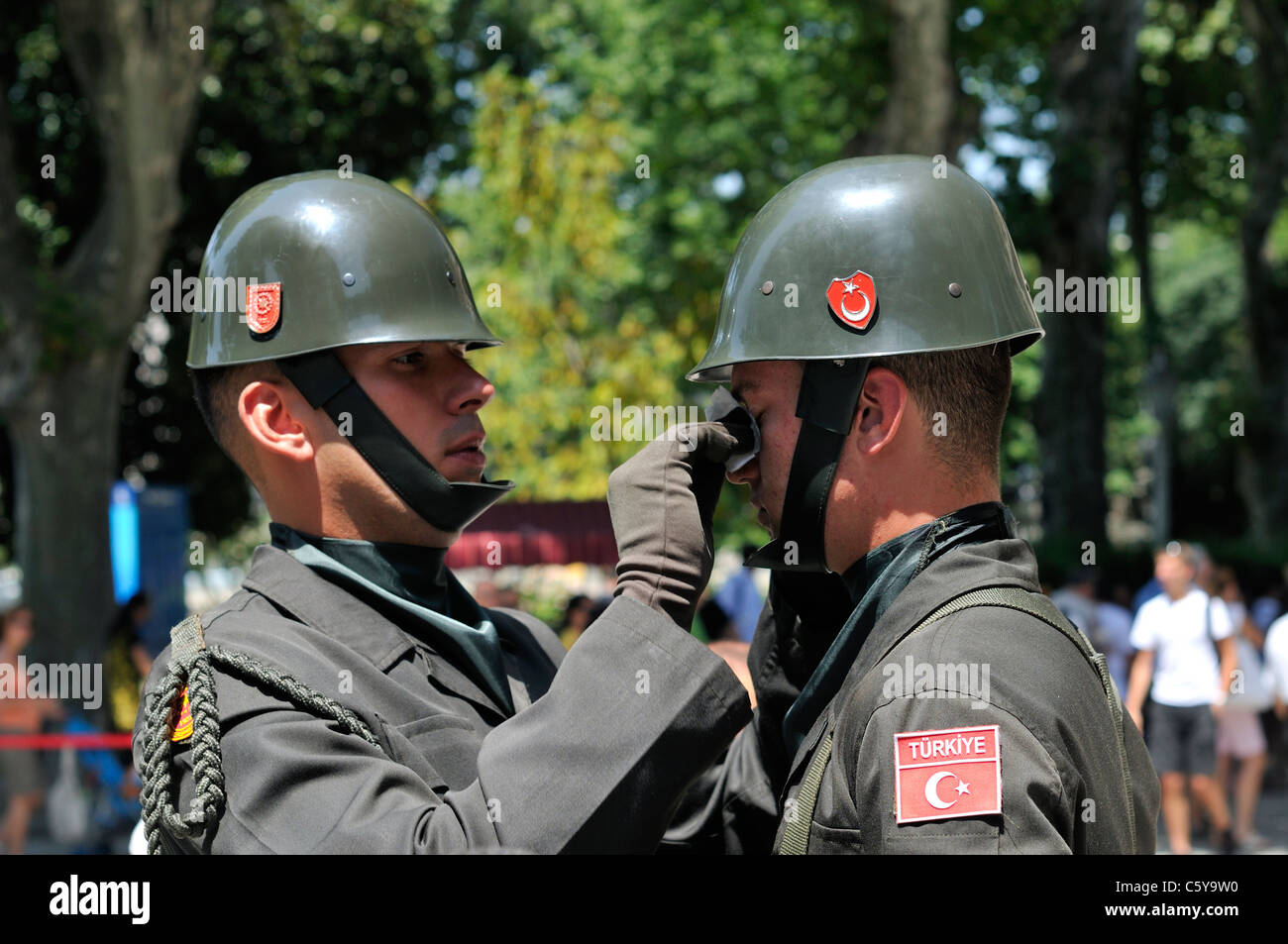 A Turkish officer wipes sweat from the brow of a soldier standing guard ...