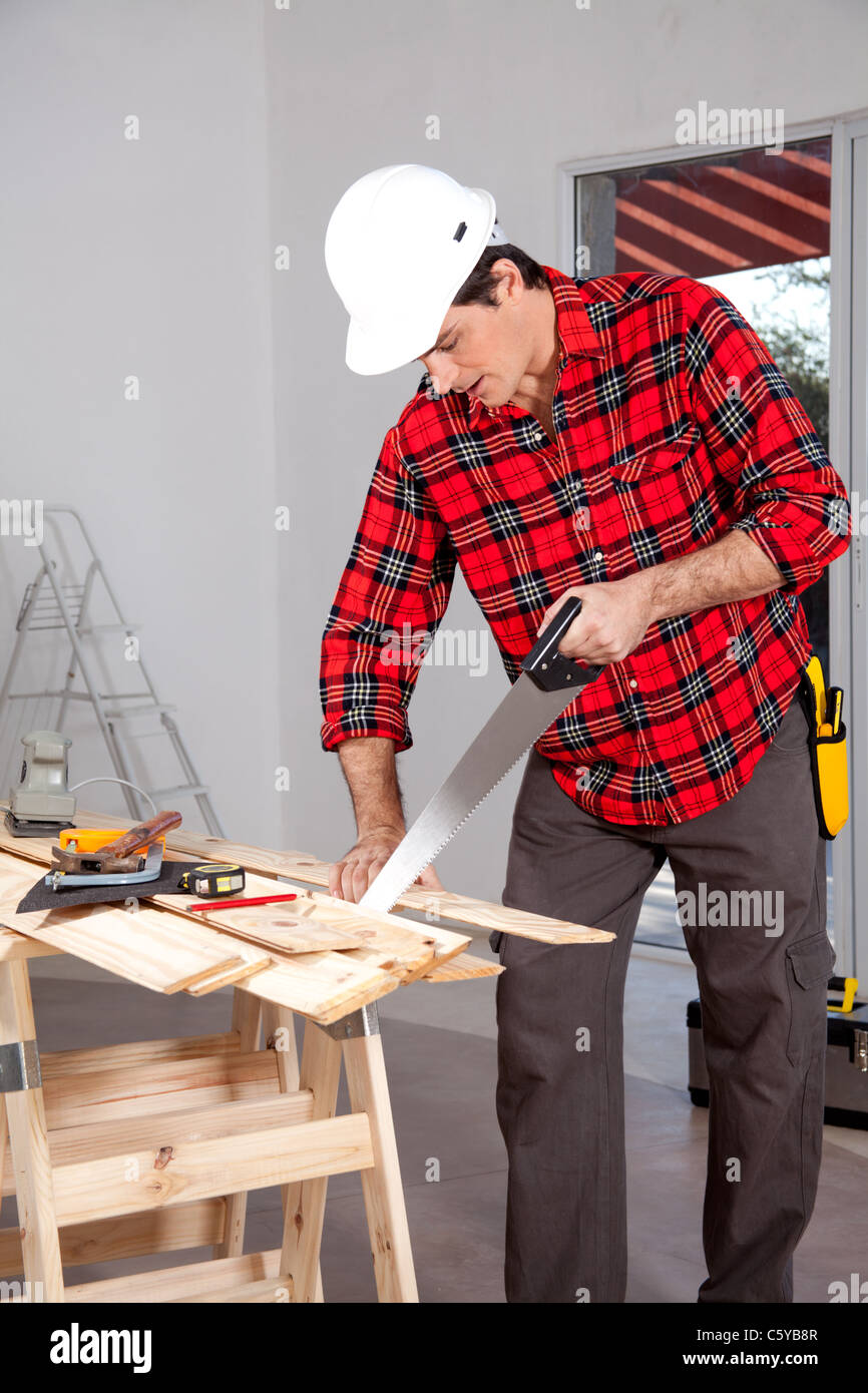 A wood worker using a hand saw in a home interior Stock Photo - Alamy