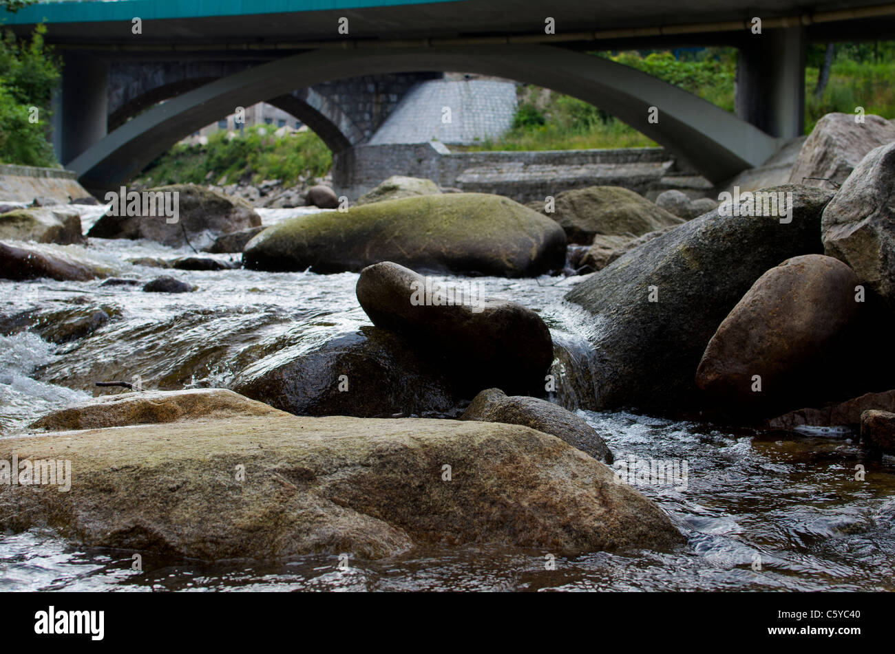 Rocks in a river and a bridge in a background Stock Photo - Alamy