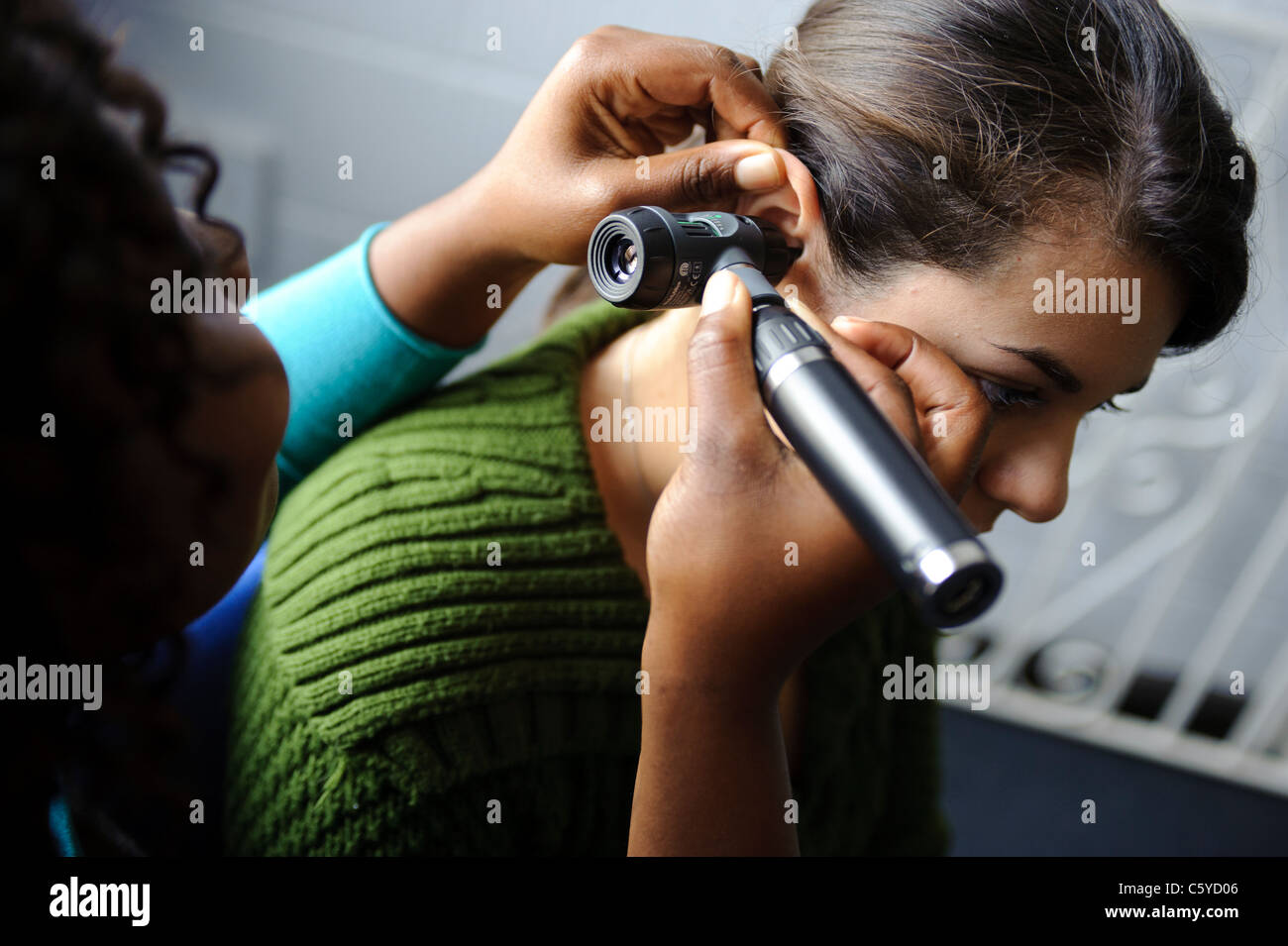 Female audiology and deafness student looking into the ear of another ...