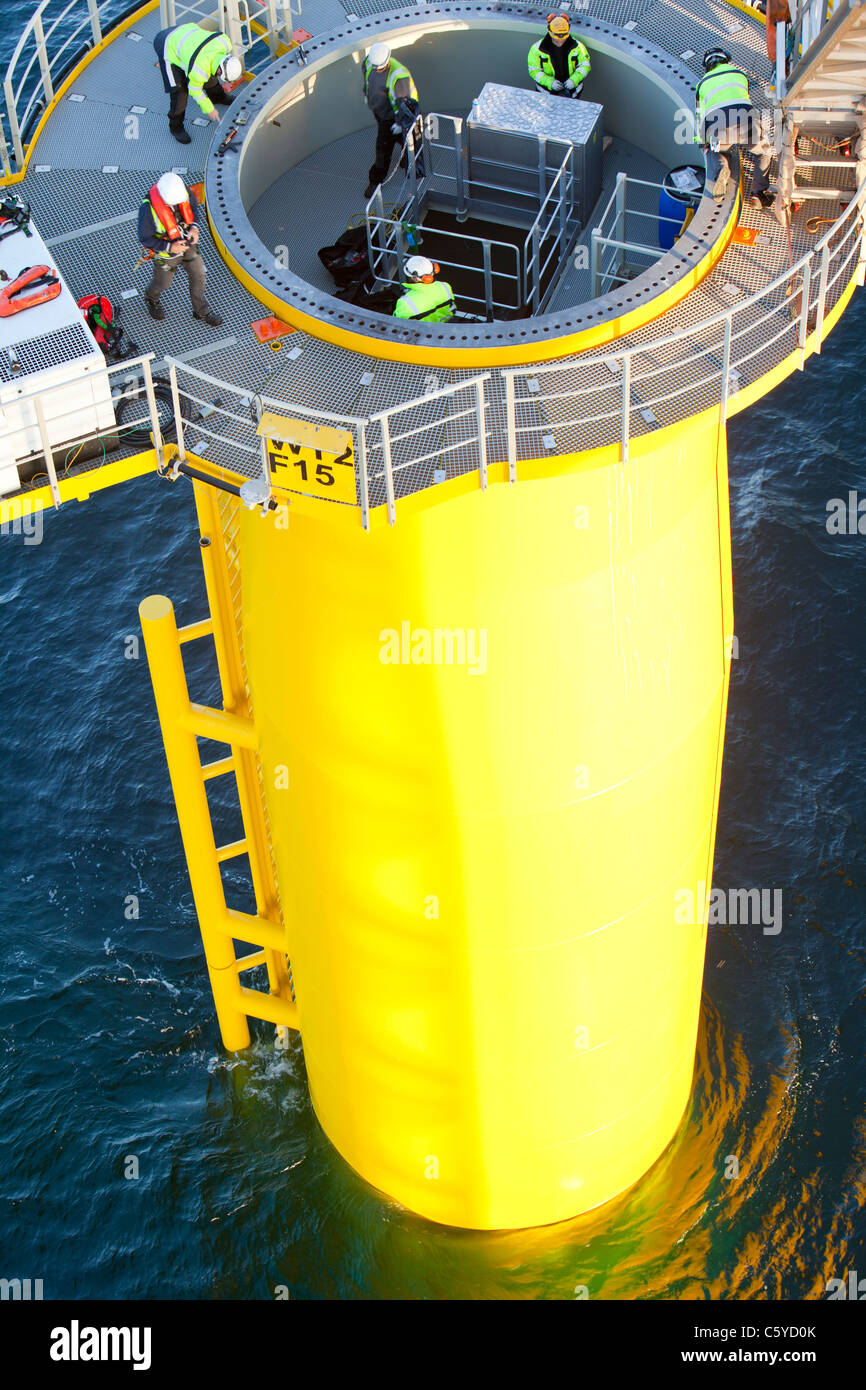 Workers on a transition piece waiting for a tower piece to be lowered ...