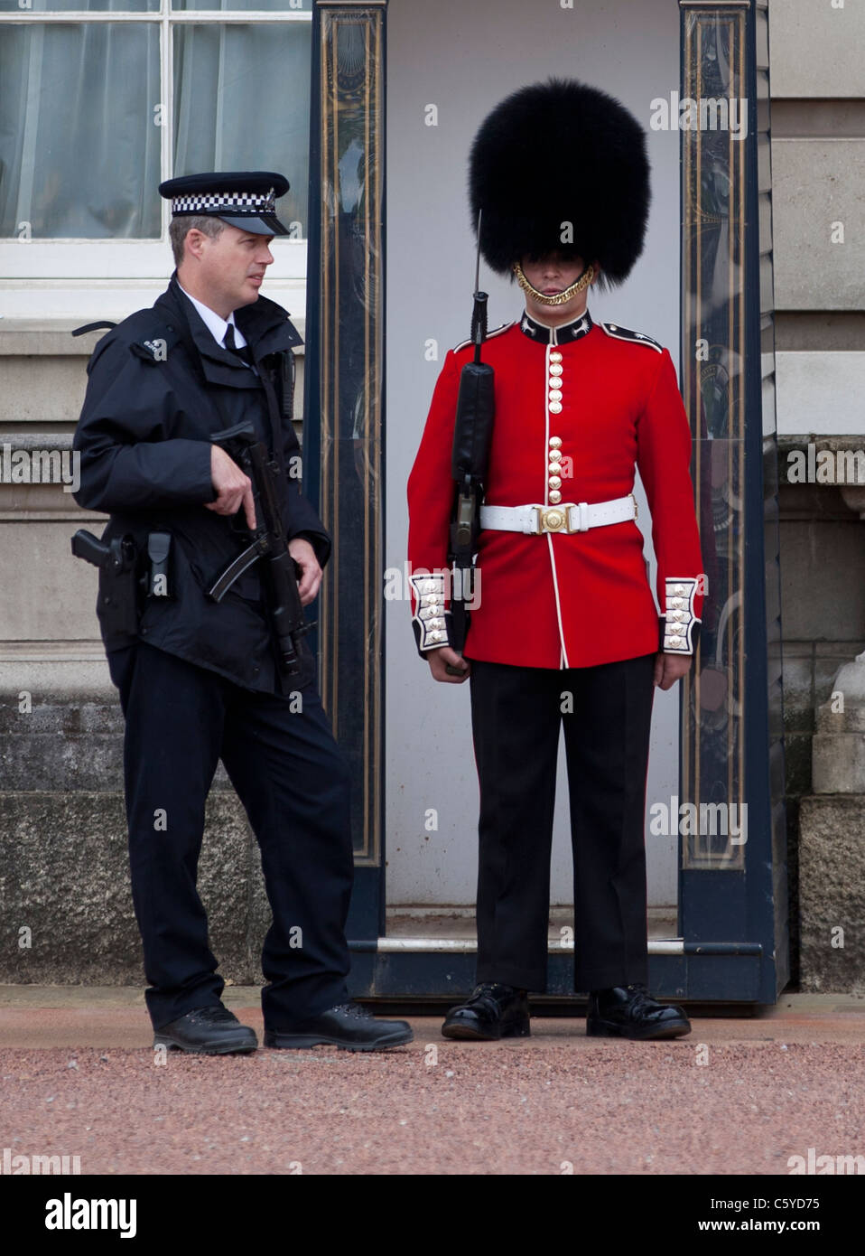 Grenadier Guard and policeman outside of Buckingham Place in London ...
