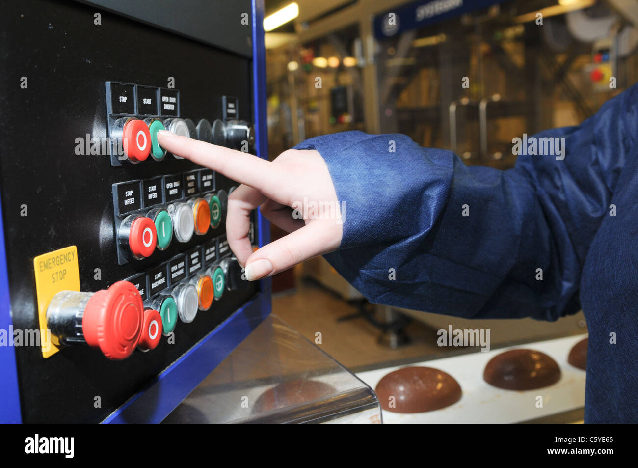 Woman's finger pressing a green go button on a chocolate factory ...