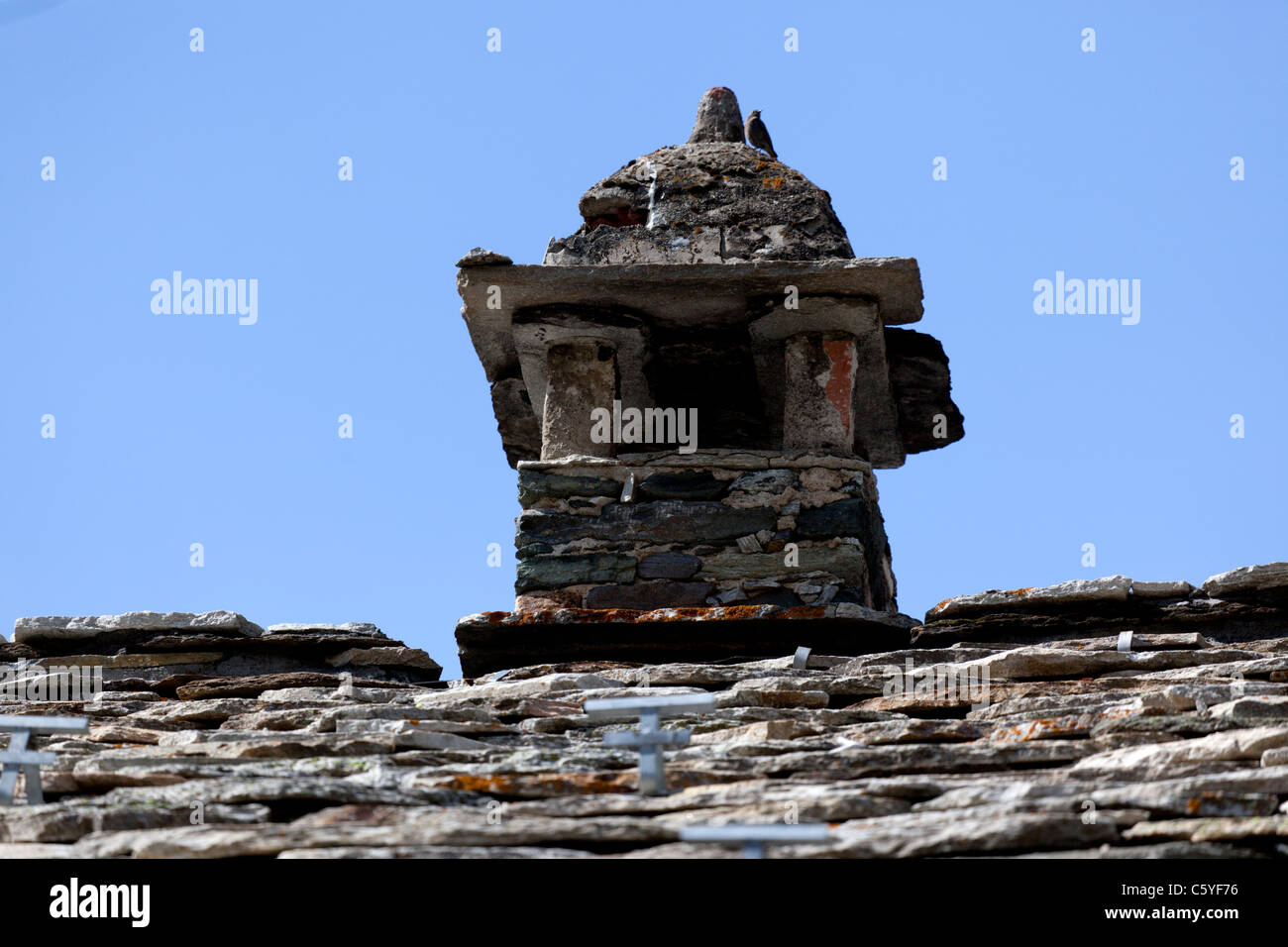 A solid chimney stack built on a roof covered with cut slates (Cogne ...