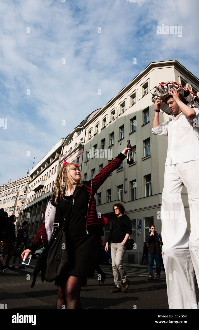 girl giving bottle of beer to man on stilts at an anarchist parade in ...