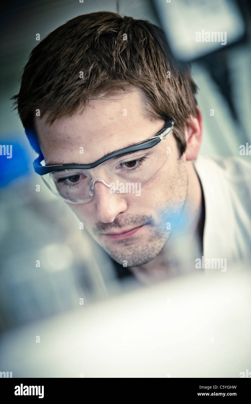 close up of face of young male scientist wearing goggles and white lab ...