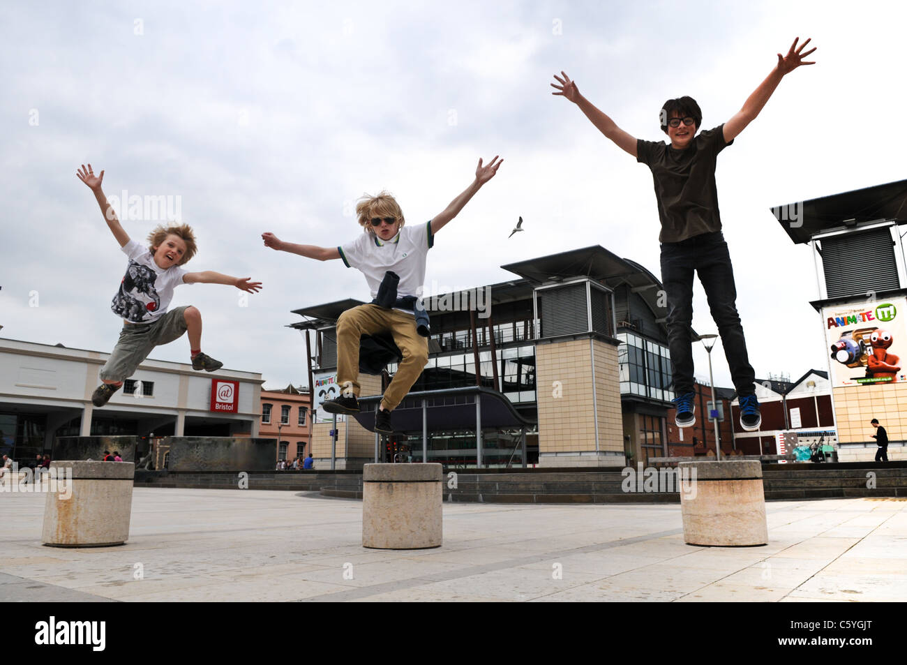 Three cool boys jumping off small pillars with their heads above the ...