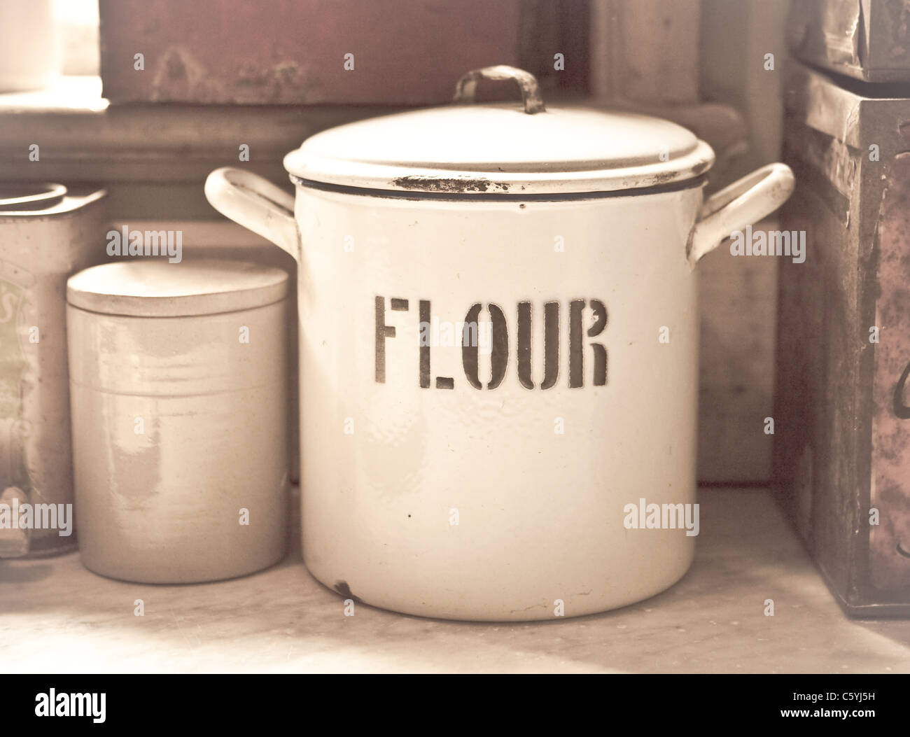 Vintage toned image of an enamel flour tin in an old style kitchen ...
