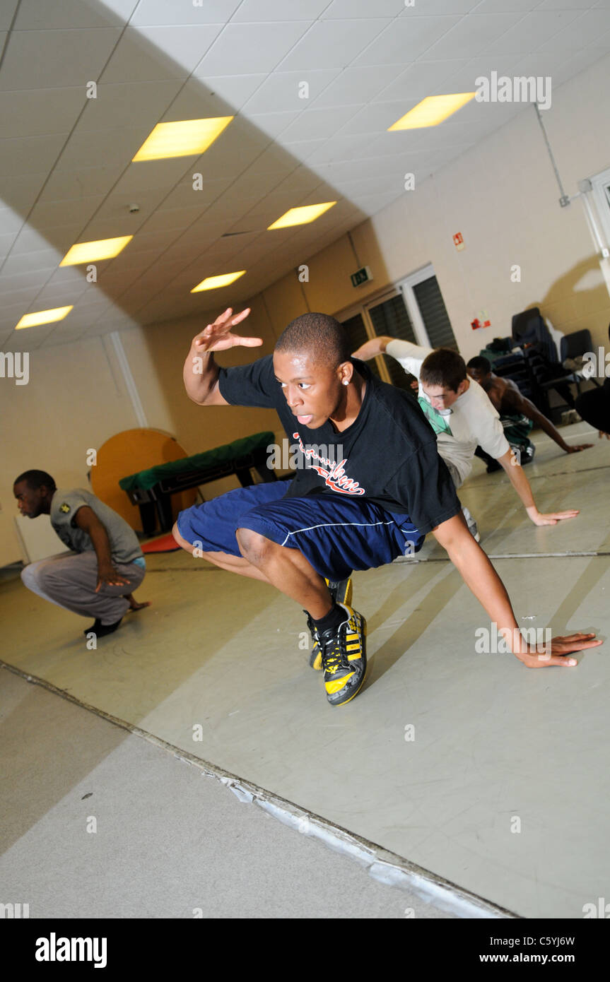 Black teenage boy in a street dance class rehearsing a dance move with ...
