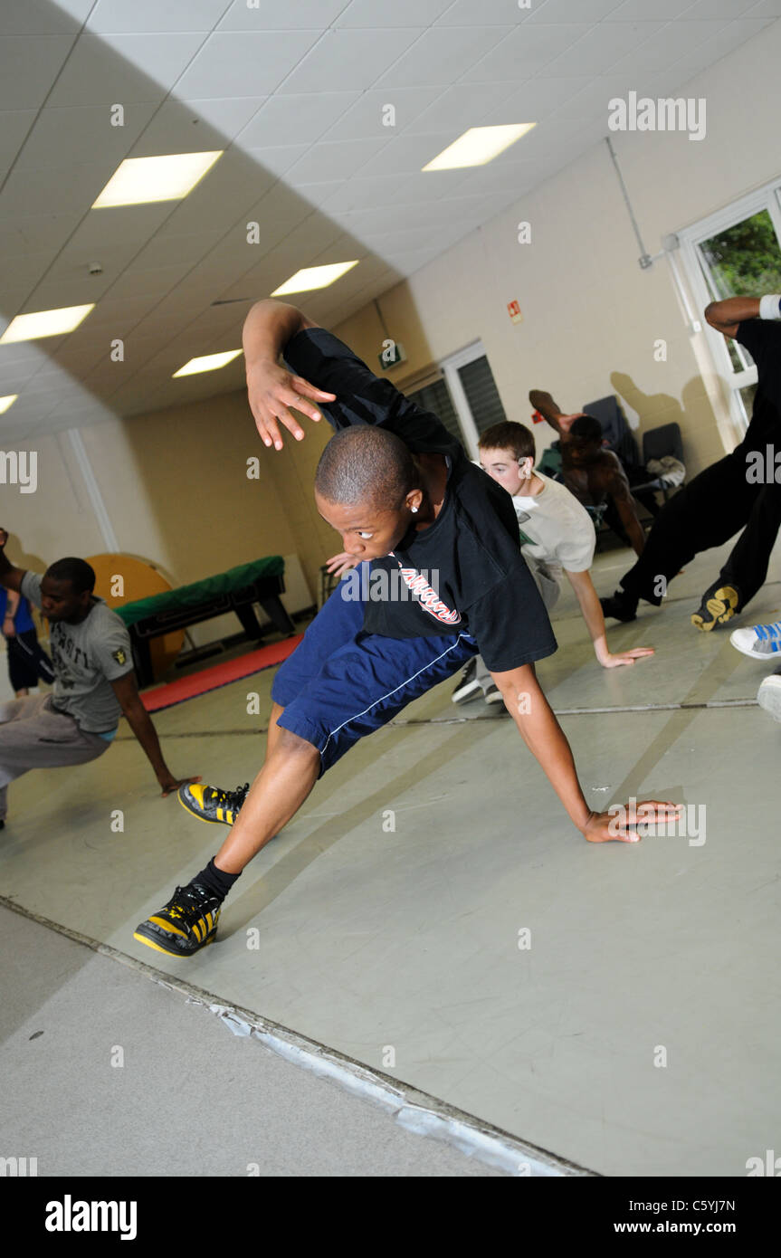 Black teenage boy in a street dance class rehearsing a dance move with ...