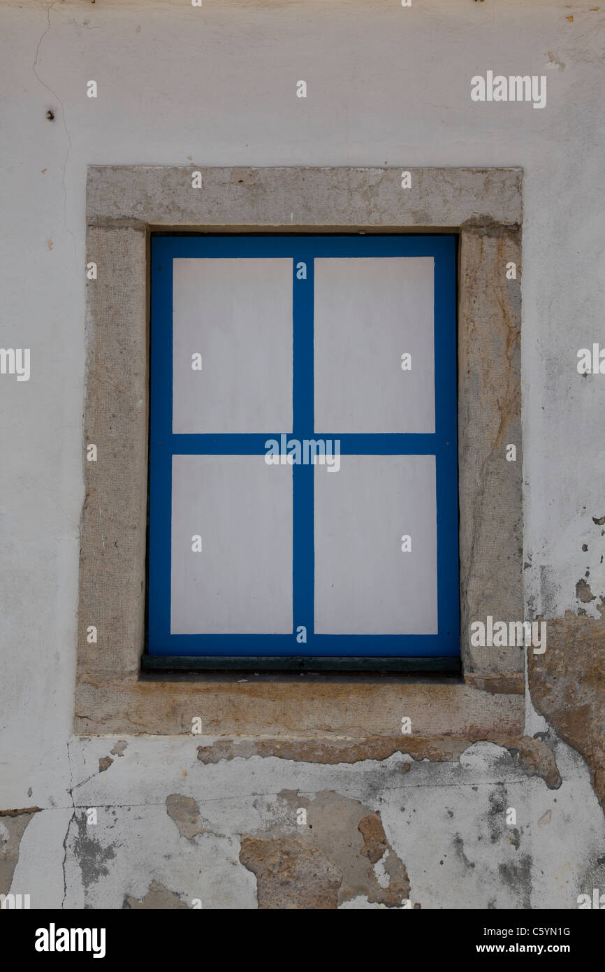 A locked out window painted in blue and white in an abandoned house ...