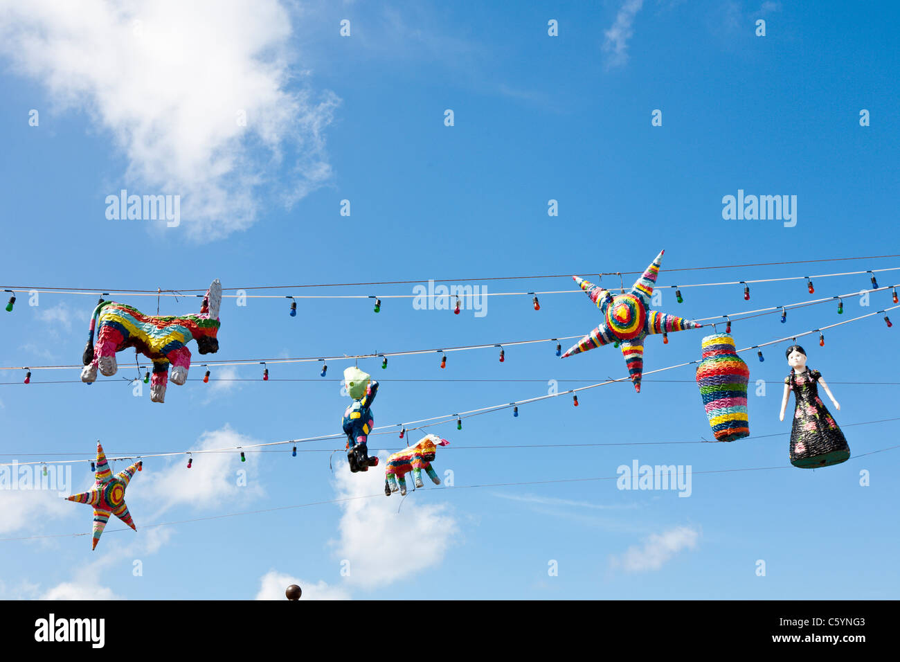 Pinatas hanging on strings of lights against blues sky in Cozumel ...