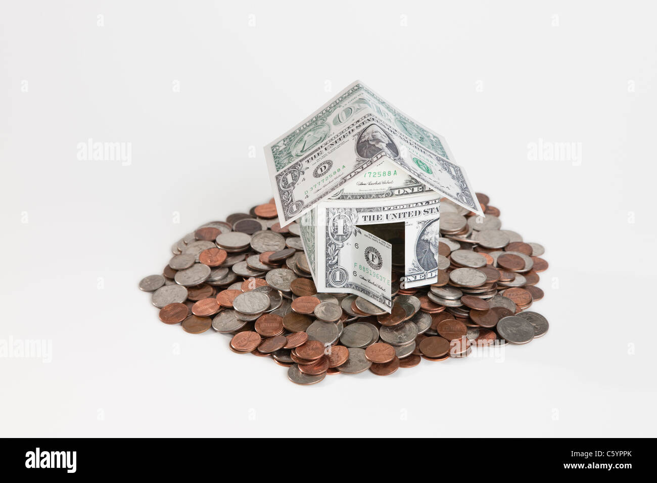Banknote house on pile of coins Stock Photo - Alamy