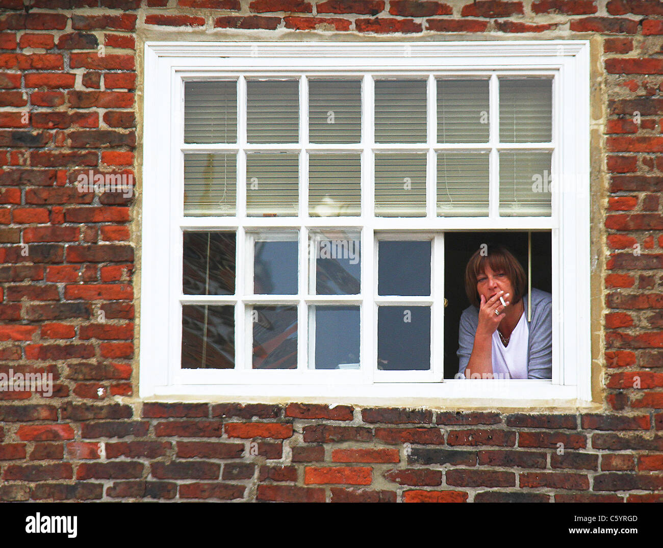 Woman smoking in window of residence in Whitby Stock Photo - Alamy